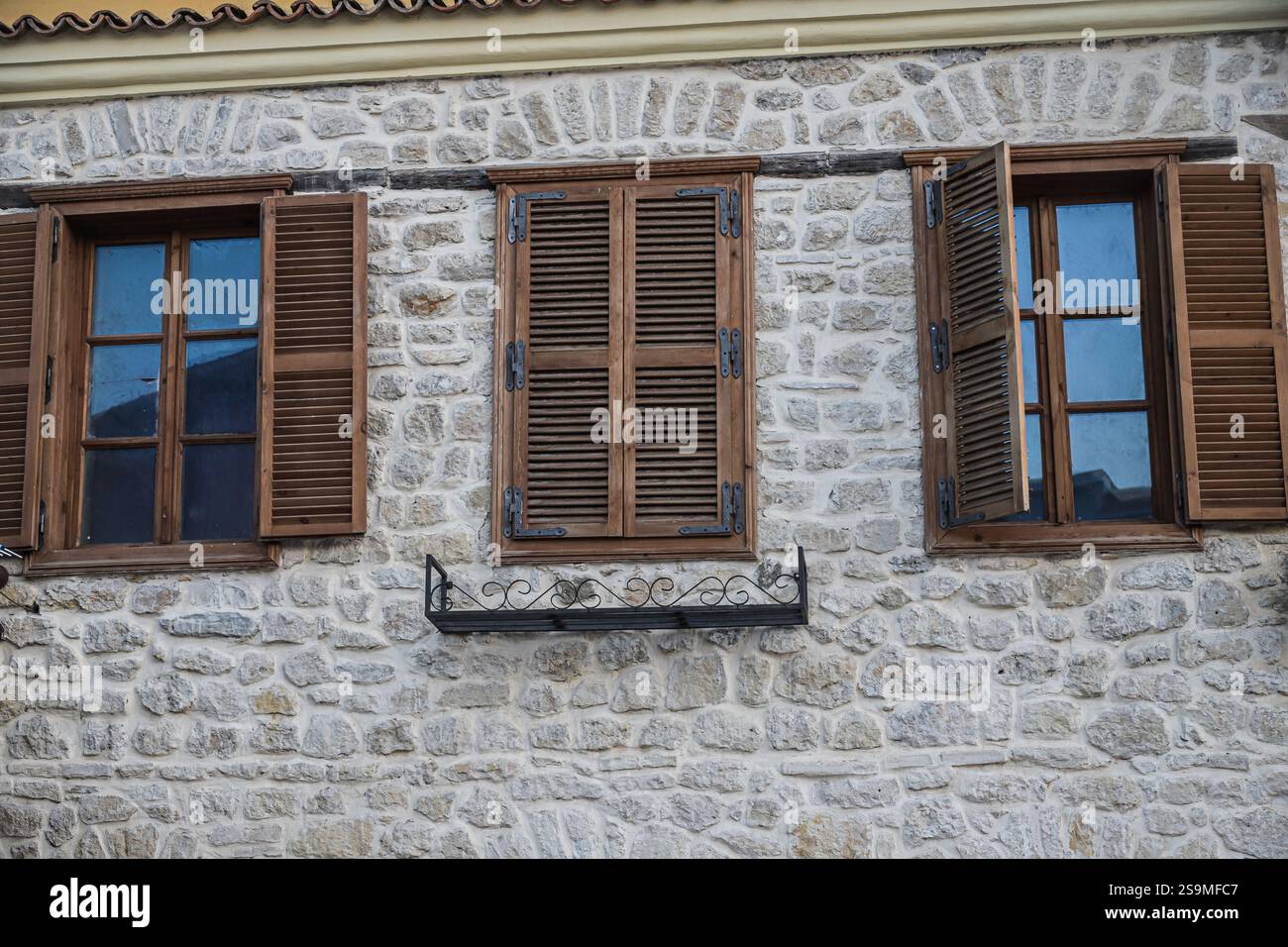 Enchanting stone wall features wooden shutters and a wrought iron ...