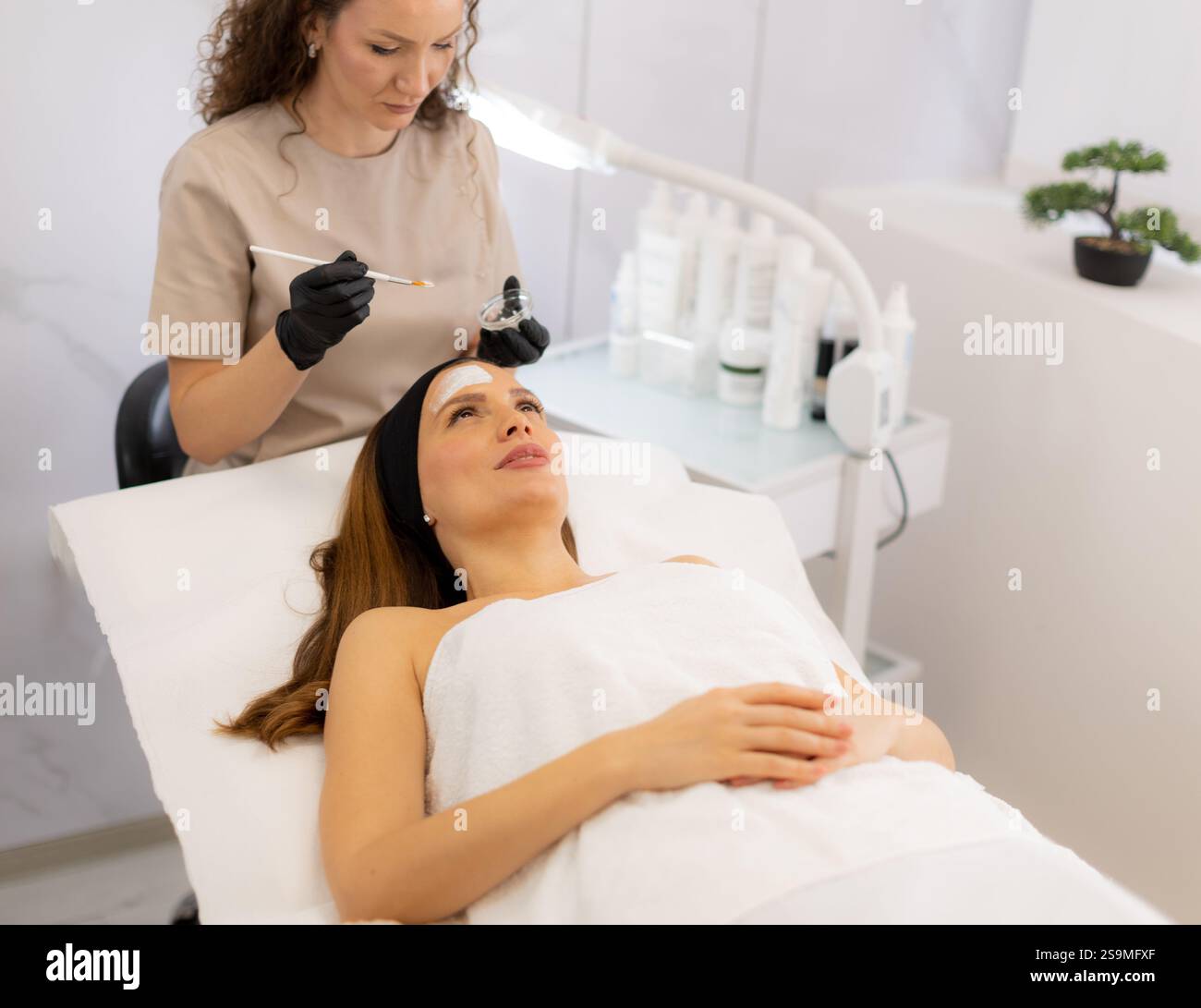 In a soothing spa setting, a patient enjoys a revitalizing facial as a ...