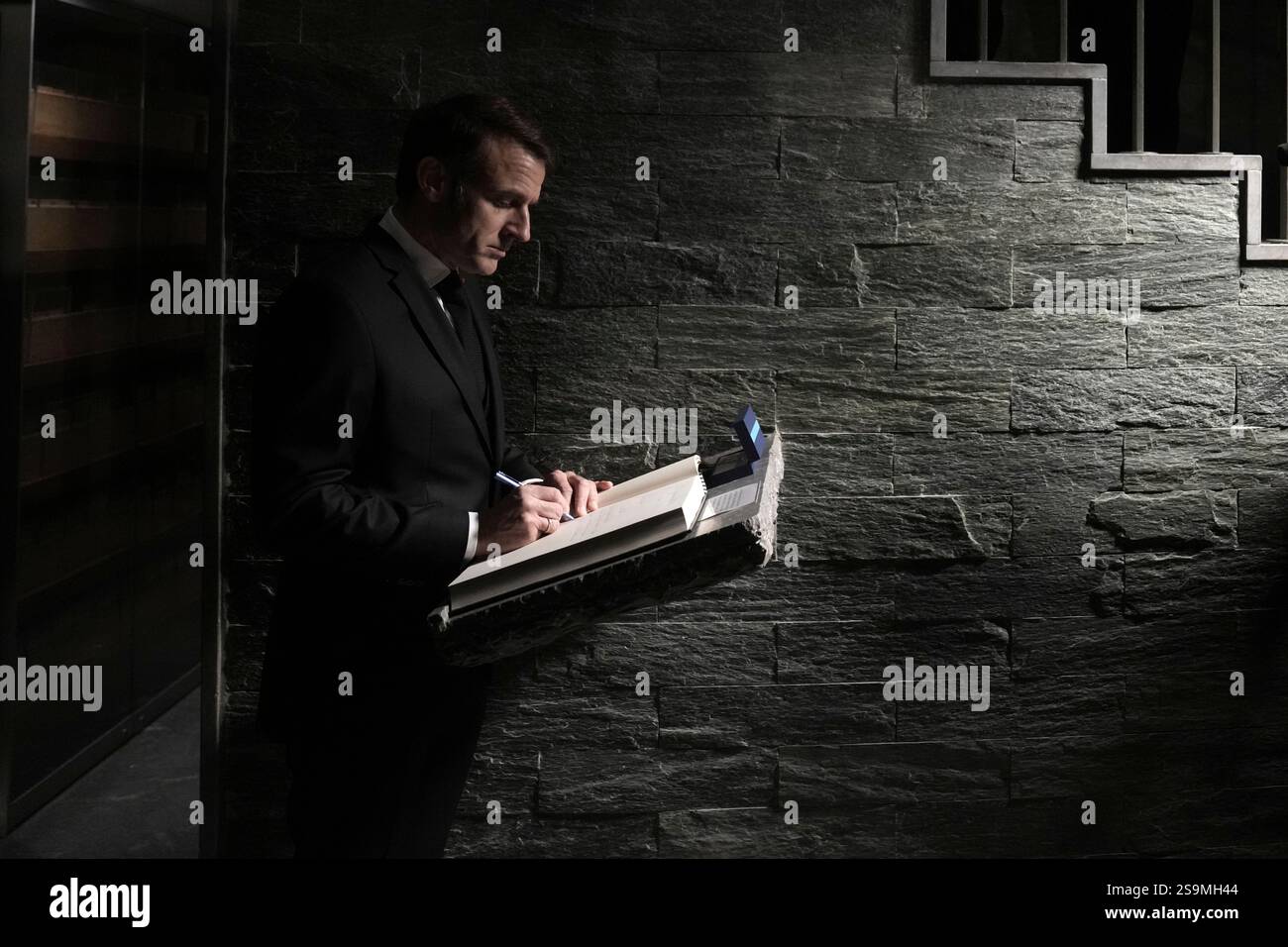 French President Emmanuel Macron signs the golden book after laying a ...