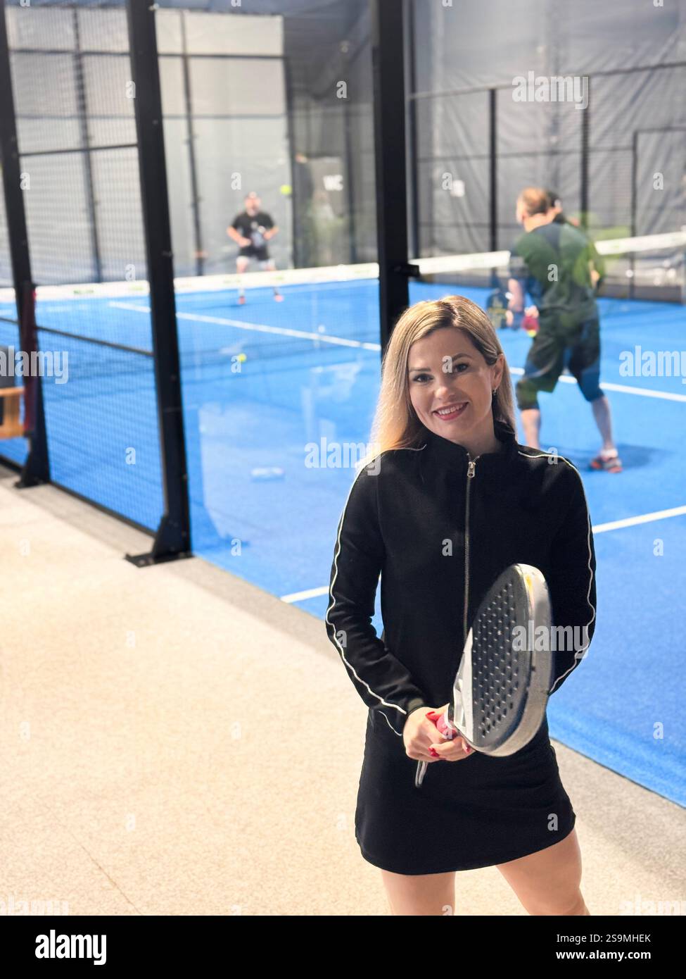 Photo of a girl behind a fence of an outdoor paddle tennis court that ...