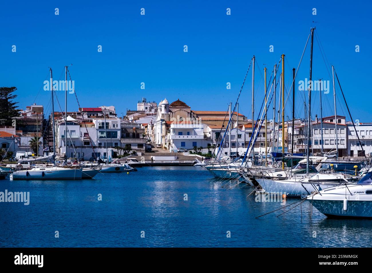 Sailing boats anchored in the marina of Calasetta, houses in the ...