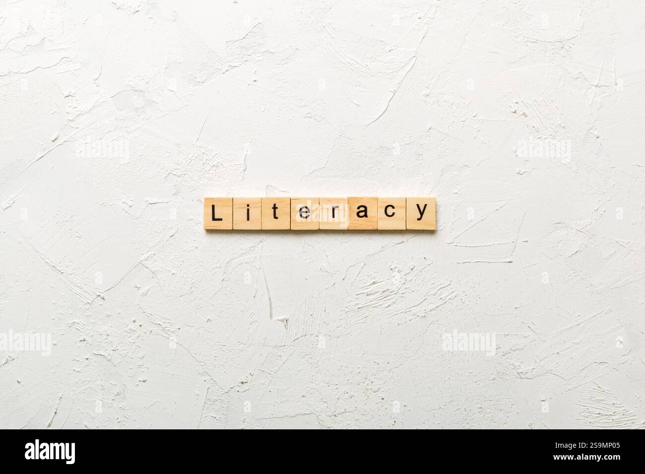 LITERACY word written on wood block. LITERACY text on cement table for ...