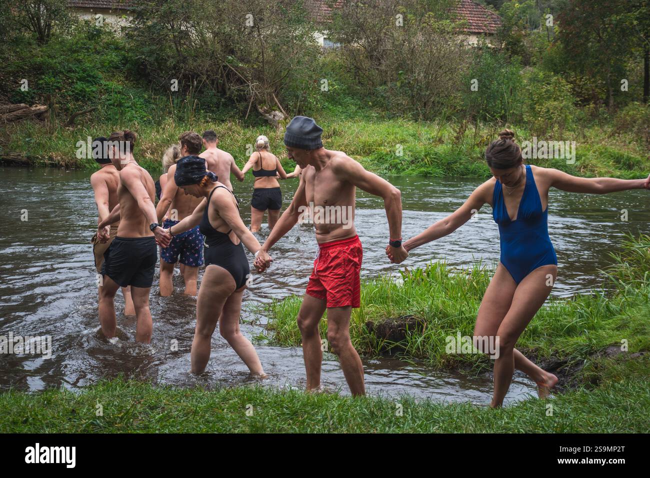 Group of people in circle ice bathing together in the cold water of a ...