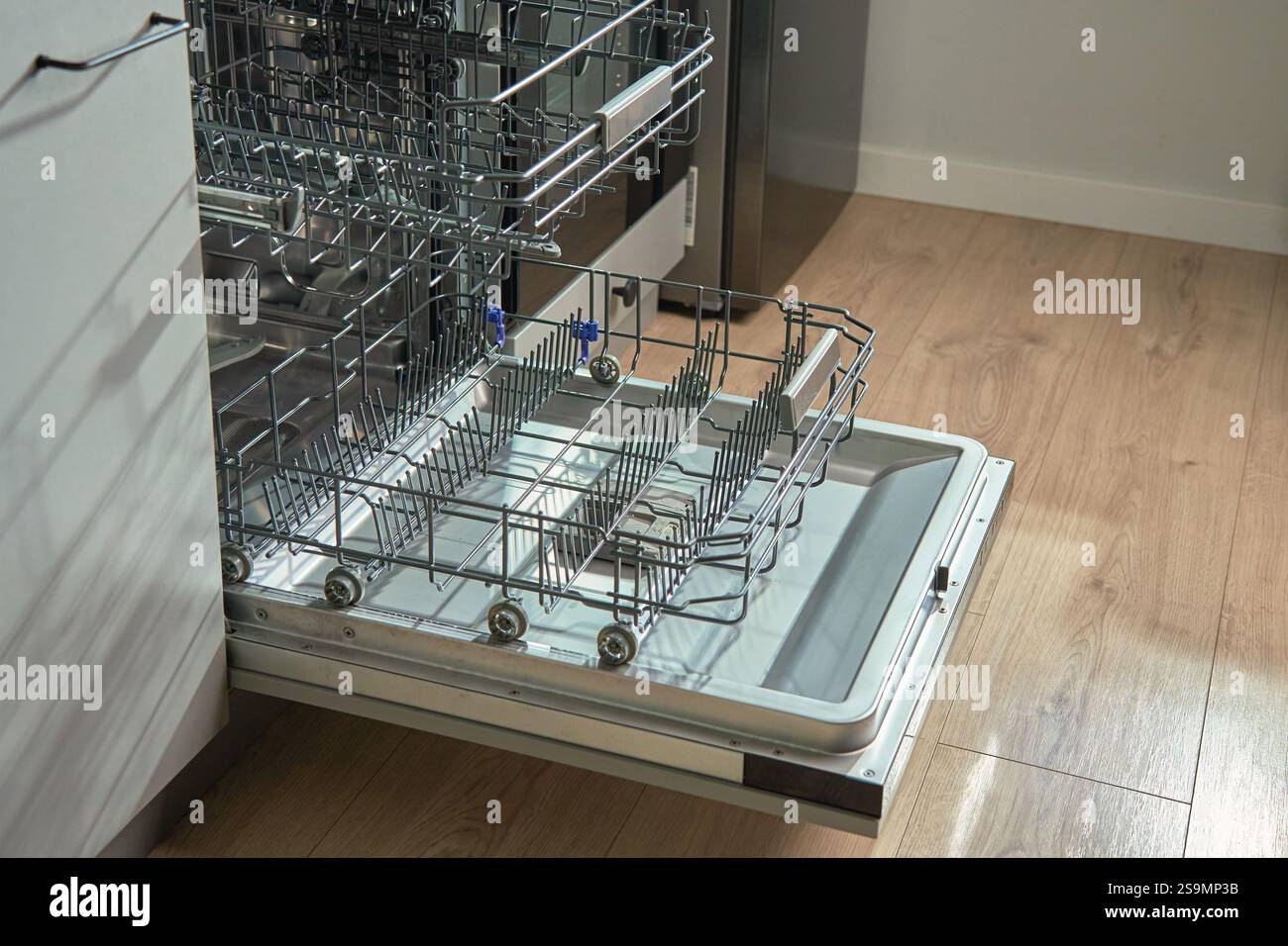 Open empty dishwasher with empty racks and extended basket in modern ...