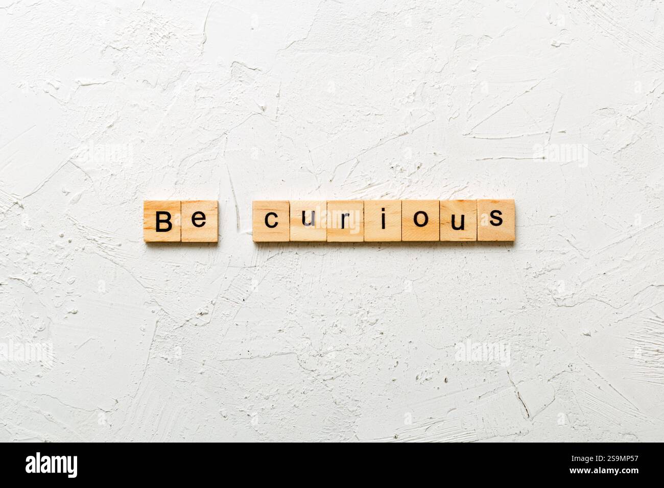 be curious word written on wood block. be curious text on table ...