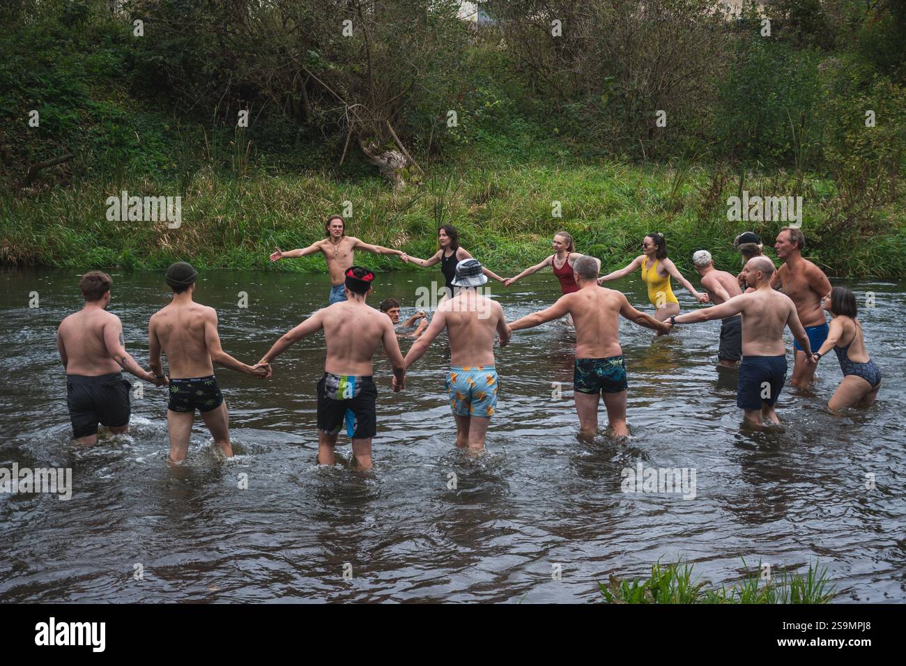 Group of people in circle ice bathing together in the cold water of a ...