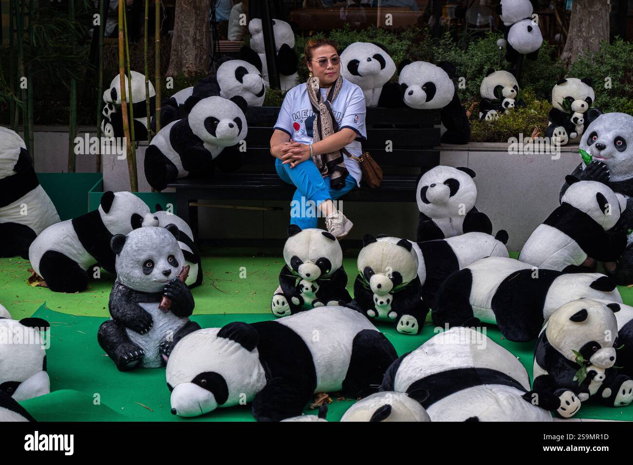 A woman poses for a photo along with the panda sculpture installations ...