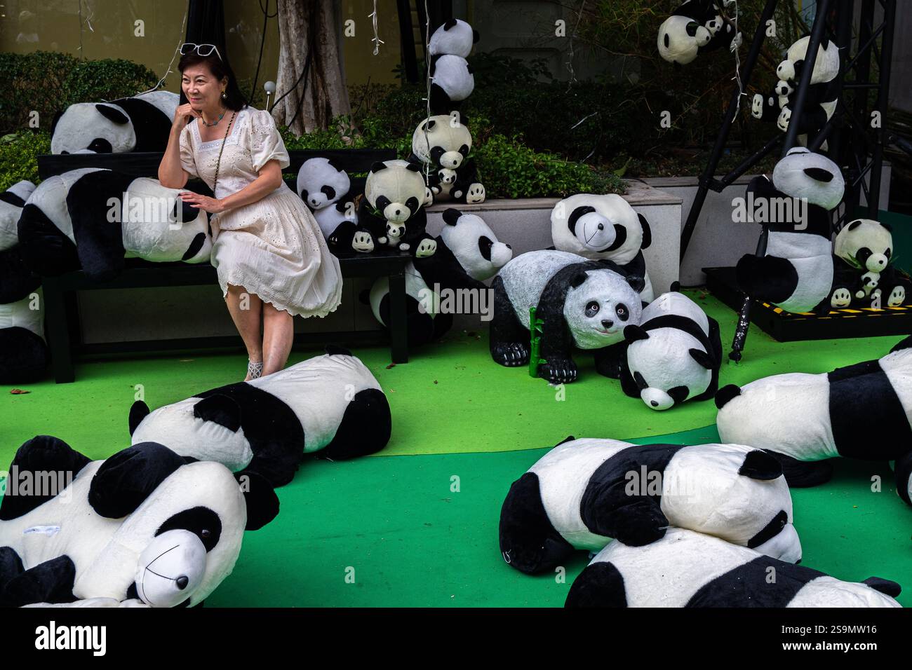 A woman poses for a photo along with the panda sculpture installations ...