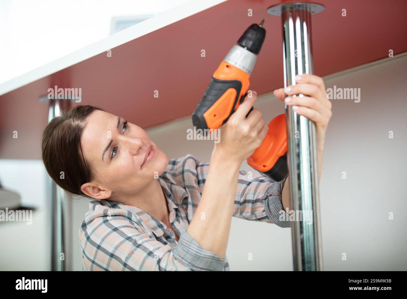 beautiful young brown-hair woman in plaid shirt working under table ...