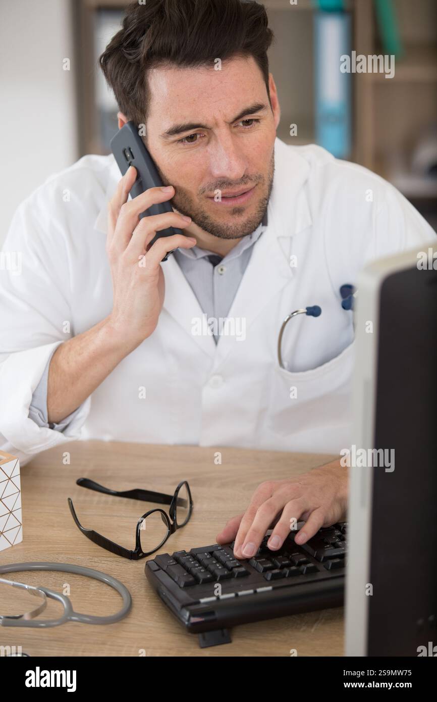 male doctor using mobile phone in clinic against computer Stock Photo ...