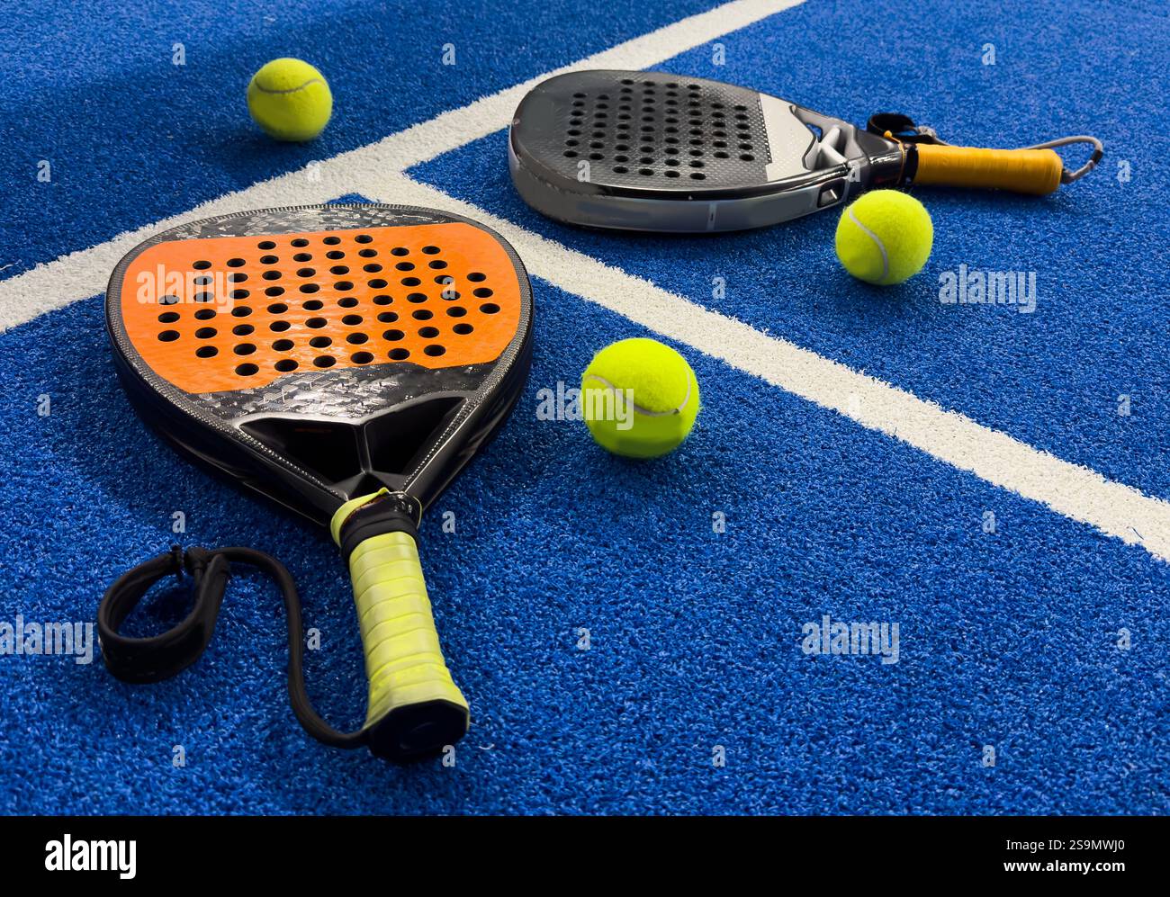 Photo of an orange padel racket and a ball on the ground of a blue ...