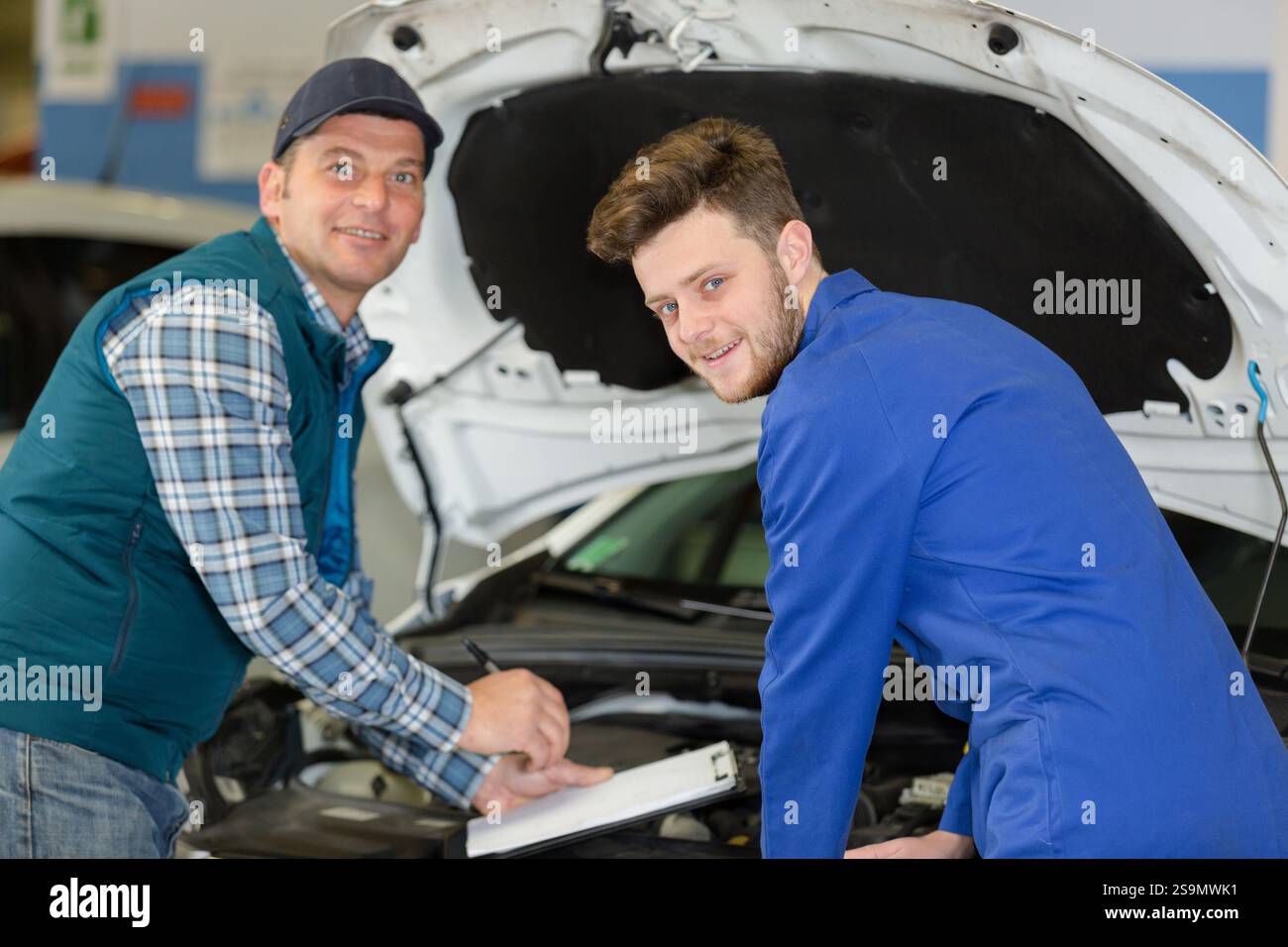 portrait of mechanic and apprentice by car with open hood Stock Photo ...