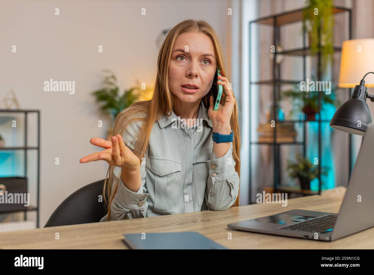 Nervous angry female manager quarrelling smartphone call online at home ...