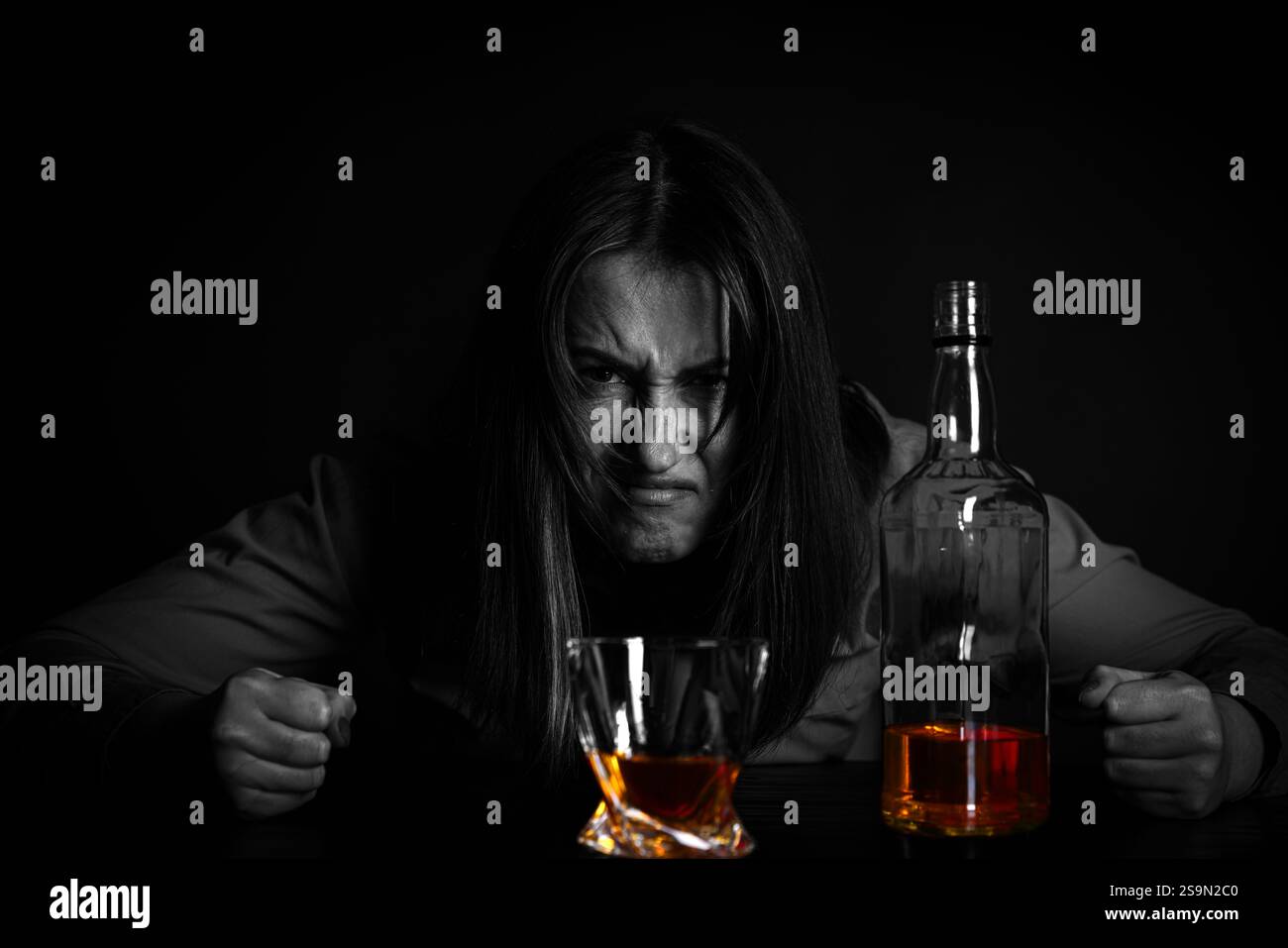 Alcohol addiction. Angry woman with whiskey at table in darkness Stock ...
