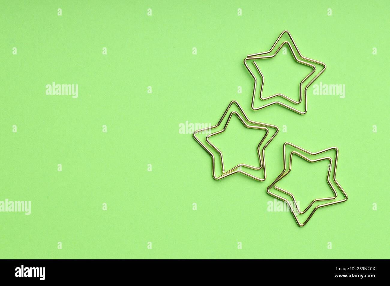 Star shaped paper clips on green background, flat lay. Space for text ...