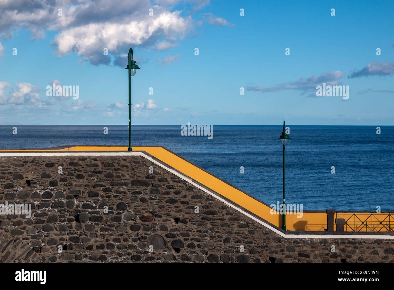 Stone bridge as a pier to the Atlantic ocean. Blue sky with white ...