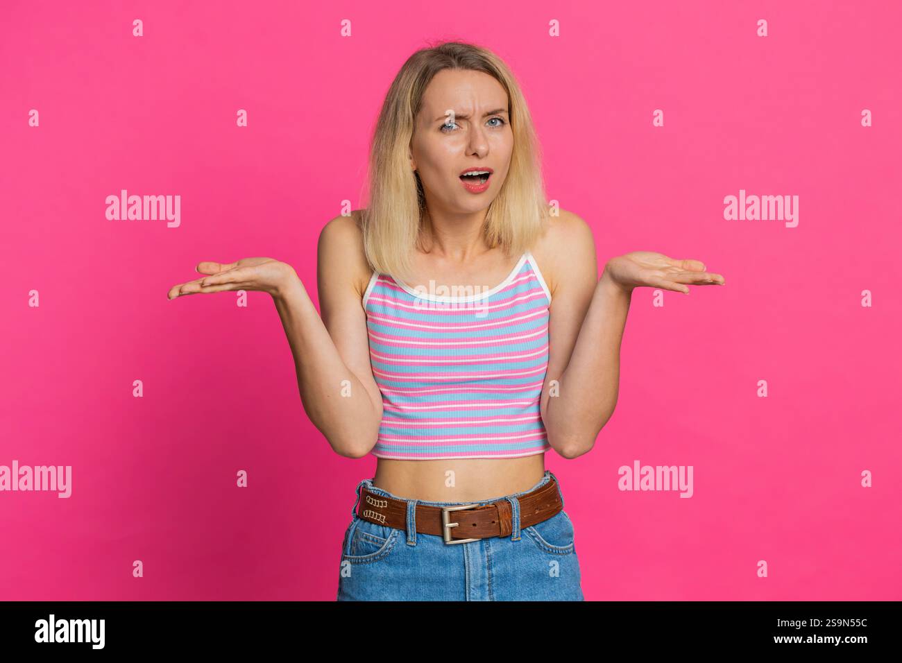 What. Why. Angry confused young woman in crop top raising hands in ...
