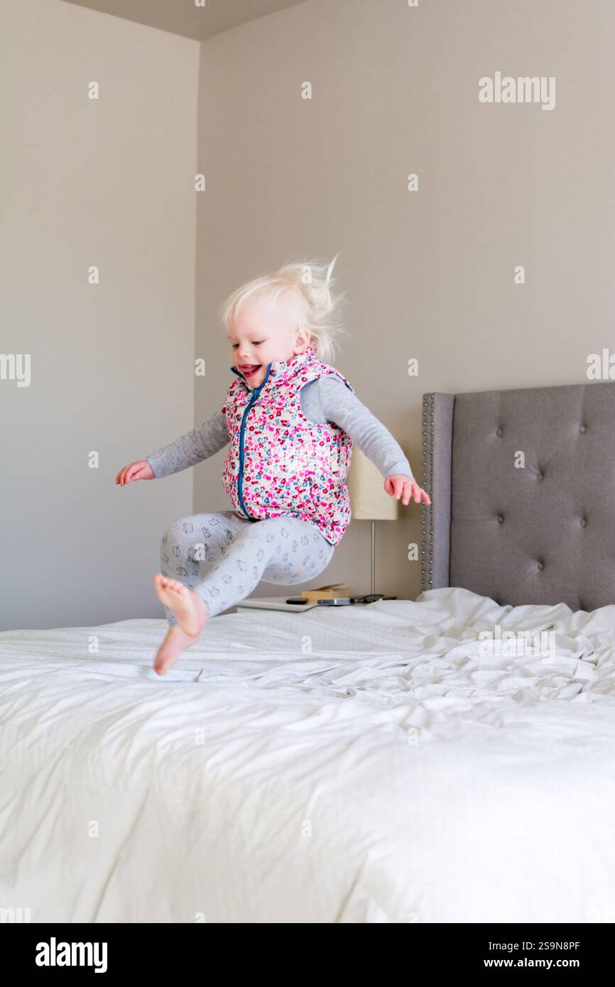 Toddler joyfully jumping on a bed Stock Photo - Alamy