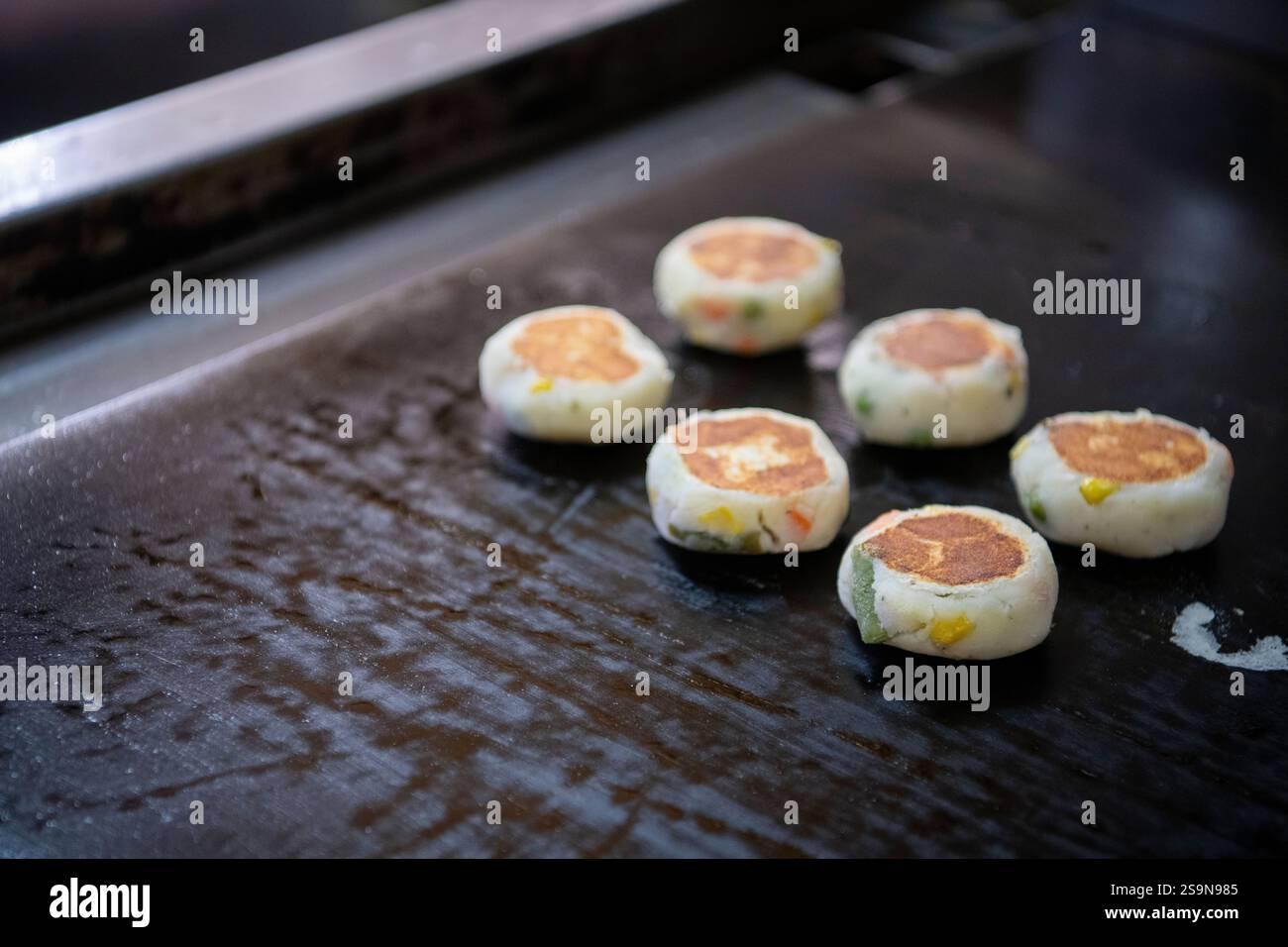 Okazuya potato vegetable hash cooking on flat black grill griddle Stock ...