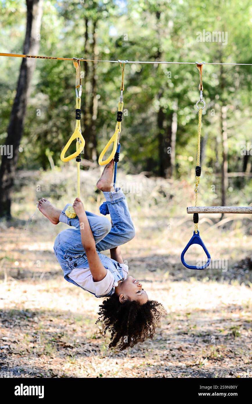 A child in overalls hangs upside down on yellow playground ropes Stock ...