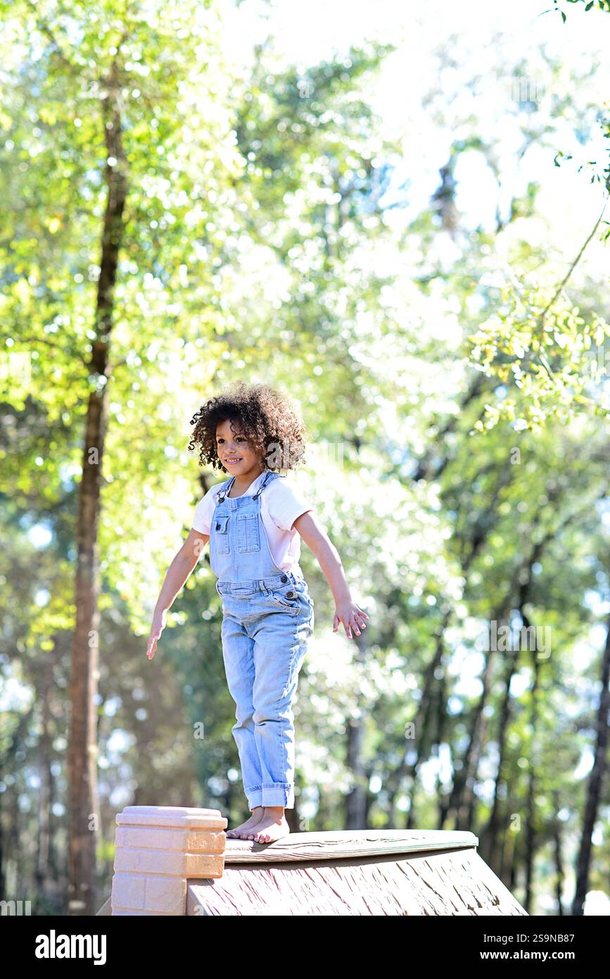 A child in overalls balances barefoot on a playhouse roof in the Stock ...