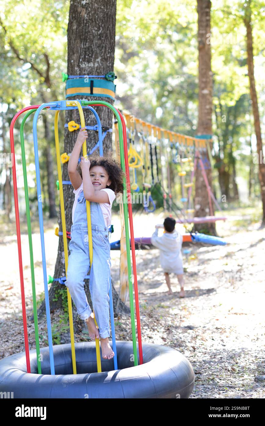 Smiling child climbing colorful poles on a play structure in a f Stock ...
