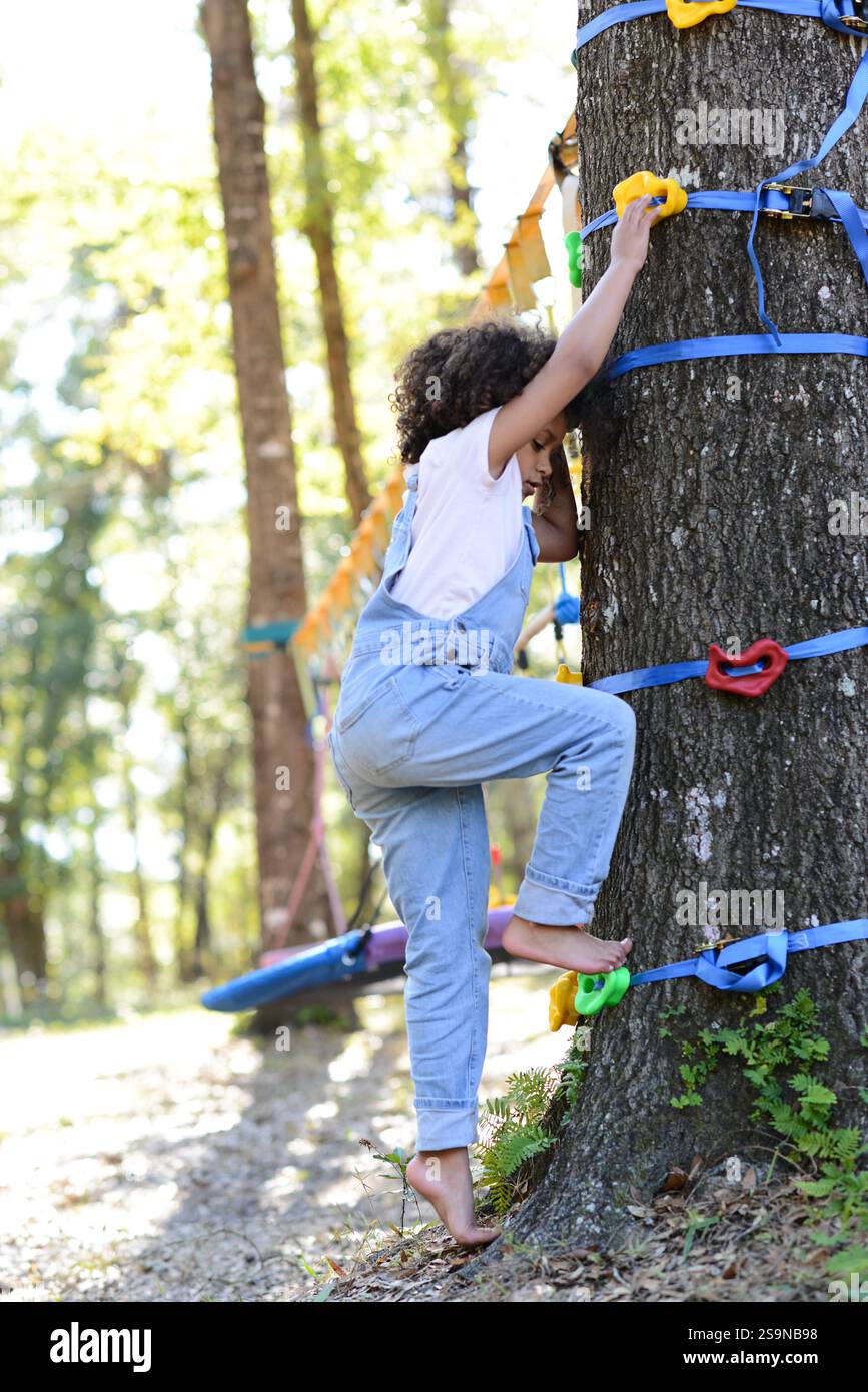 Child climbing a tree with colorful grips, barefoot, focused in Stock ...