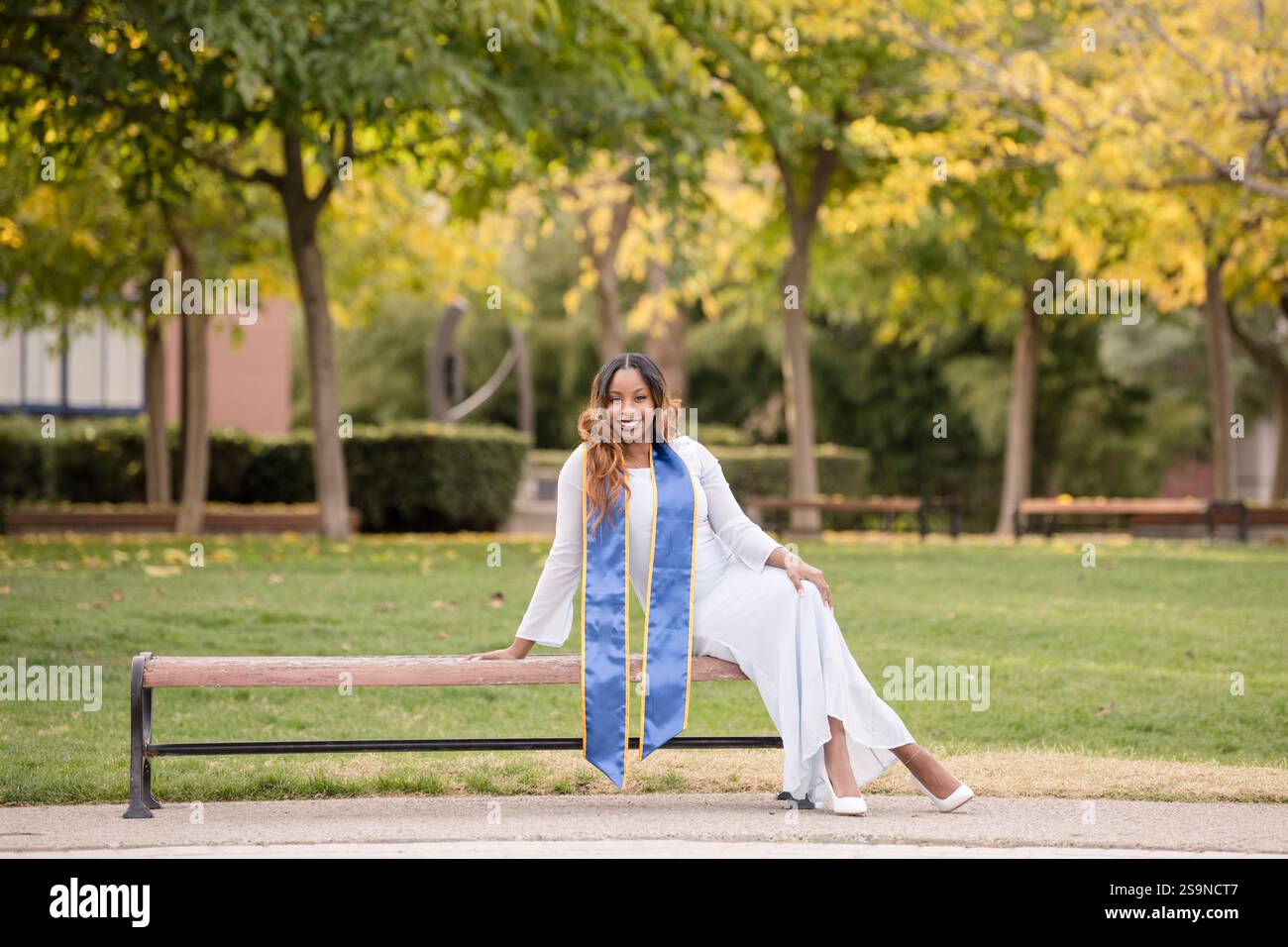 Woman smiling wearing graduation sash Stock Photo - Alamy