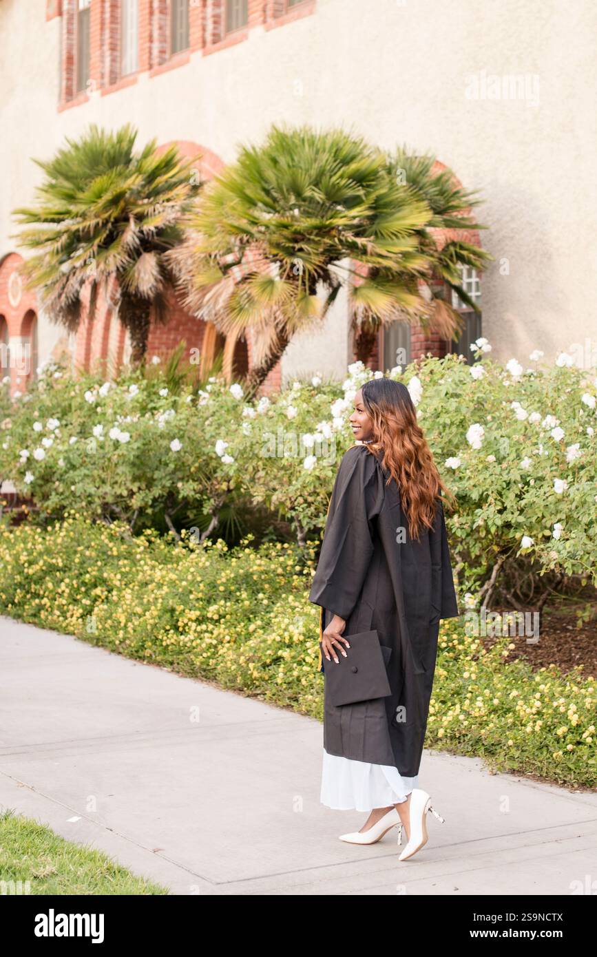 Woman graduate holding cap walking away Stock Photo - Alamy