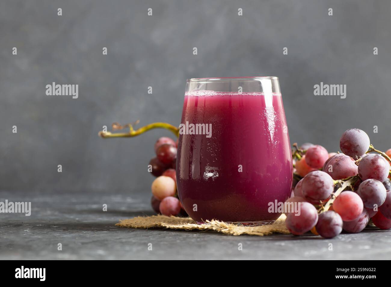 Glass of black or red grape fruit compote juice with fresh grapes ...