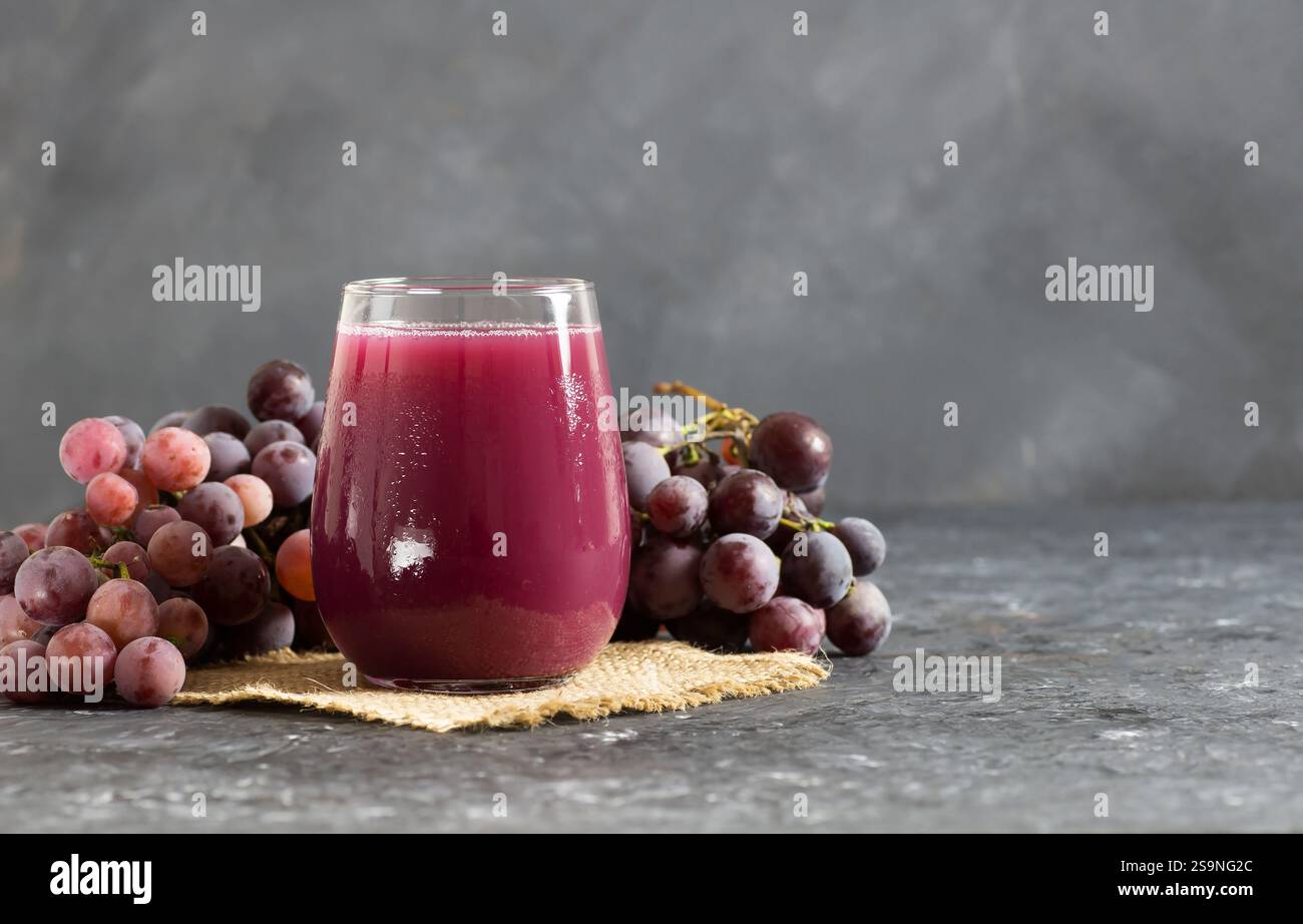Glass of black or red grape fruit compote juice with fresh grapes ...