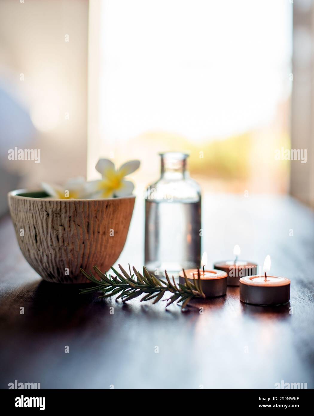 Flowers, rosemary in water and candles in spa for wellness or beauty ...