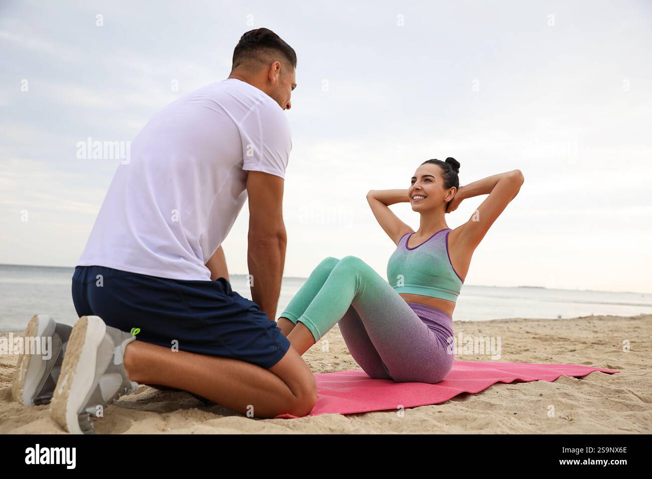 Couple doing exercise together on beach. Body training Stock Photo - Alamy