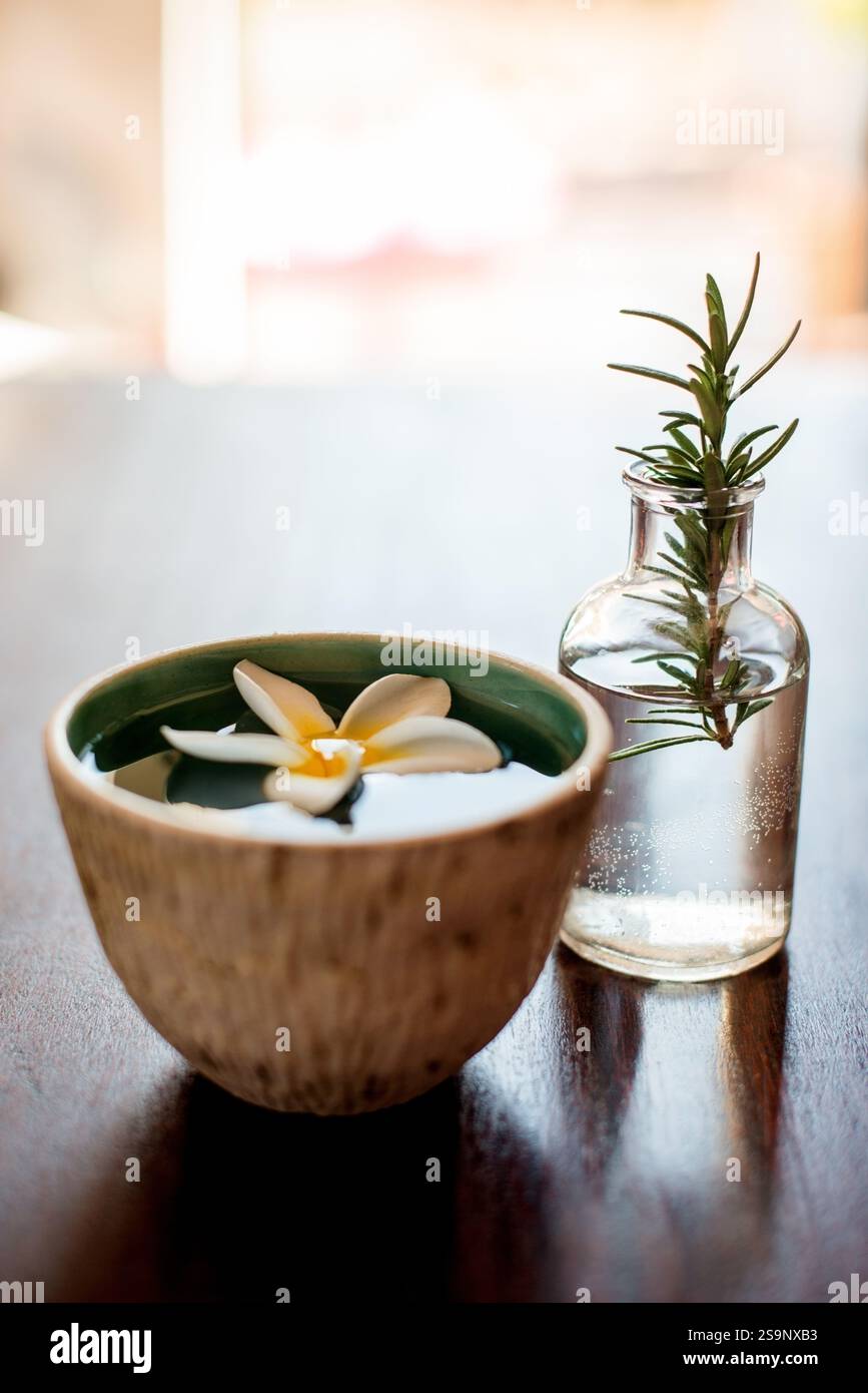 Flowers, rosemary and bowl of water in spa for skincare, wellness and ...
