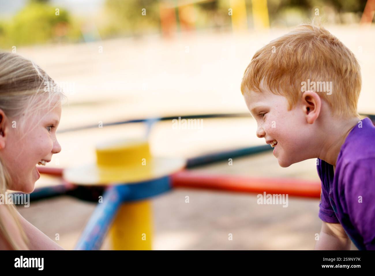 Happy kids, spin and playground with fun childhood on merry go round or ...