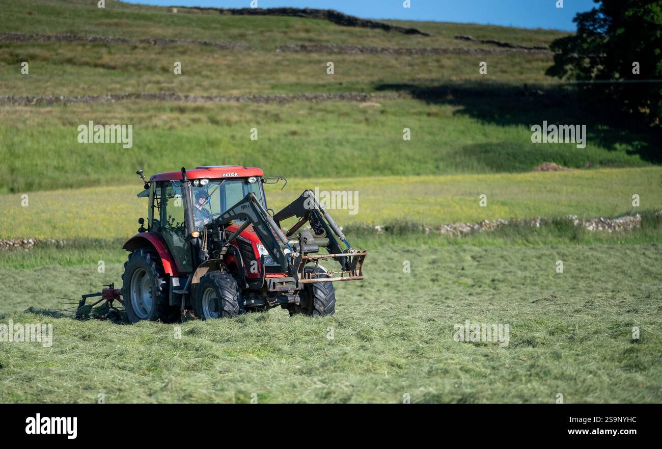 A Zetor tractor spreading grass out to make hay near tan hill Stock ...