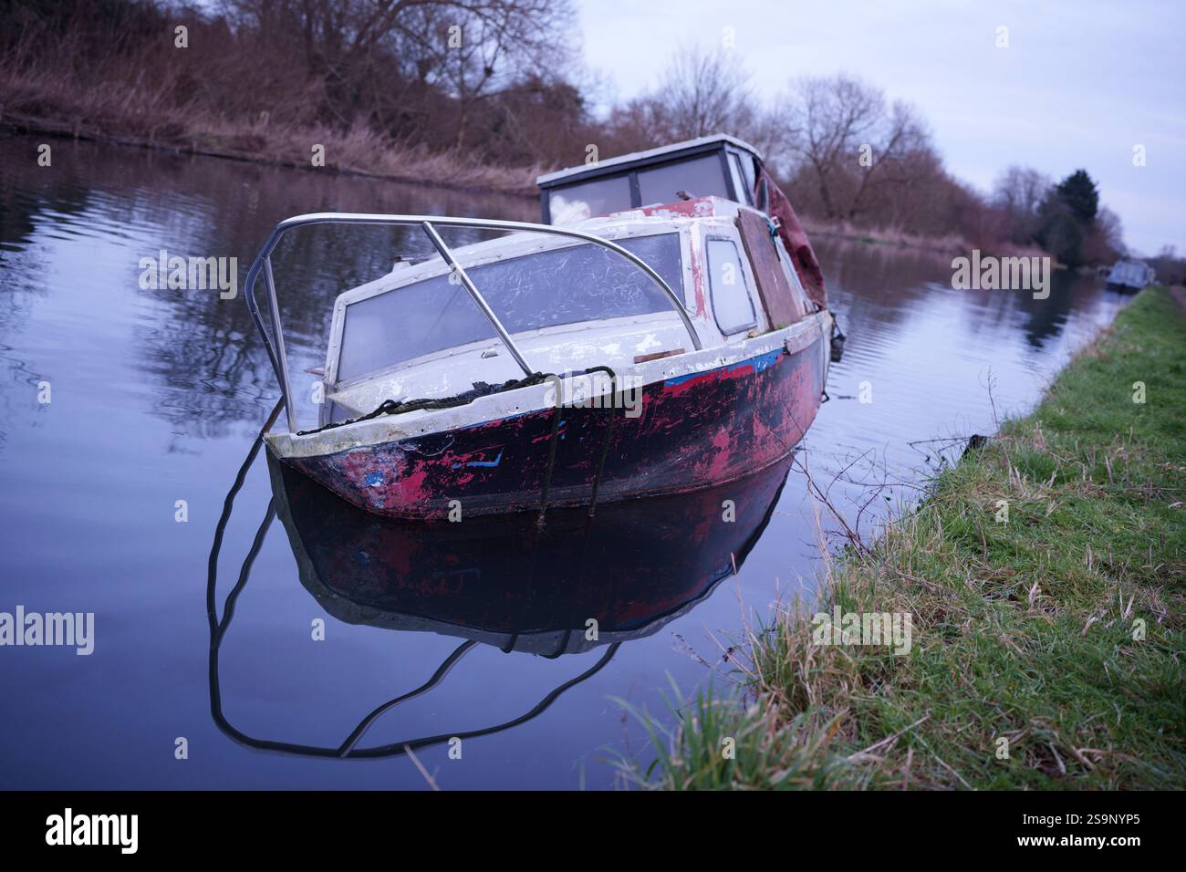 A small pleasure boat lies half-submerged next to the towpath on the Grand Union Canal, on 25th ...