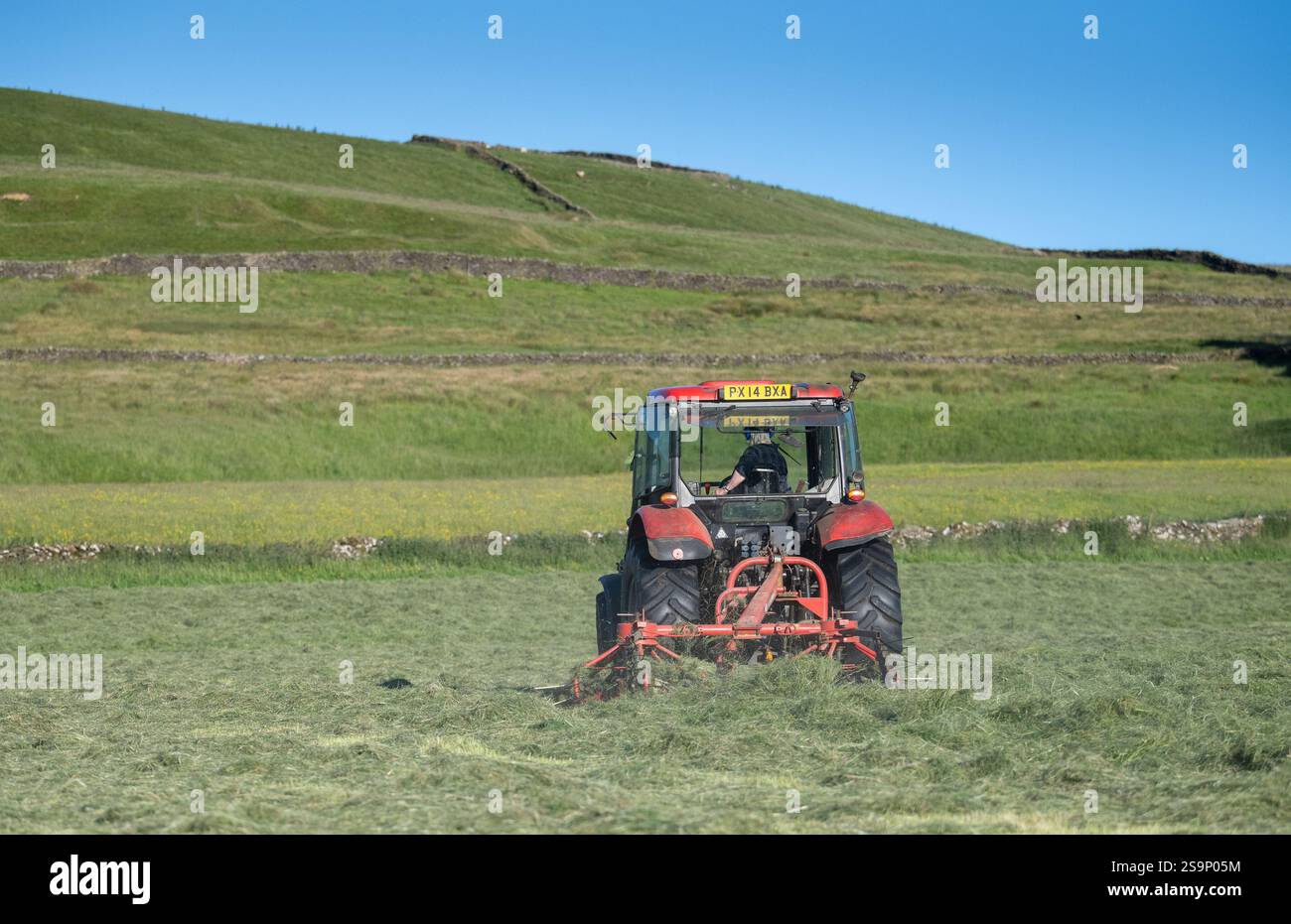A Zetor tractor spreading grass out to make hay near tan hill Stock ...
