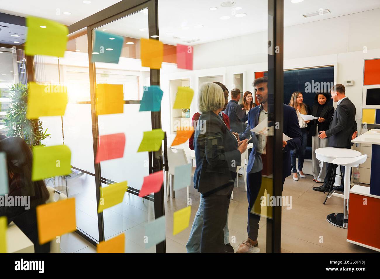 Multiracial colleagues working inside business office with glass walls ...
