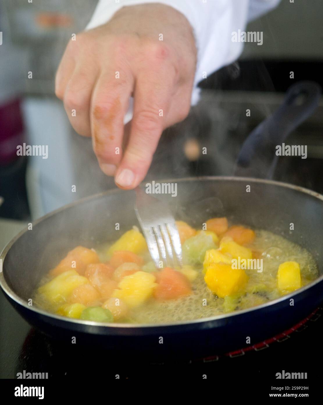 Stirring food in a pan with a fork. Making dinner. Chef at work in the ...