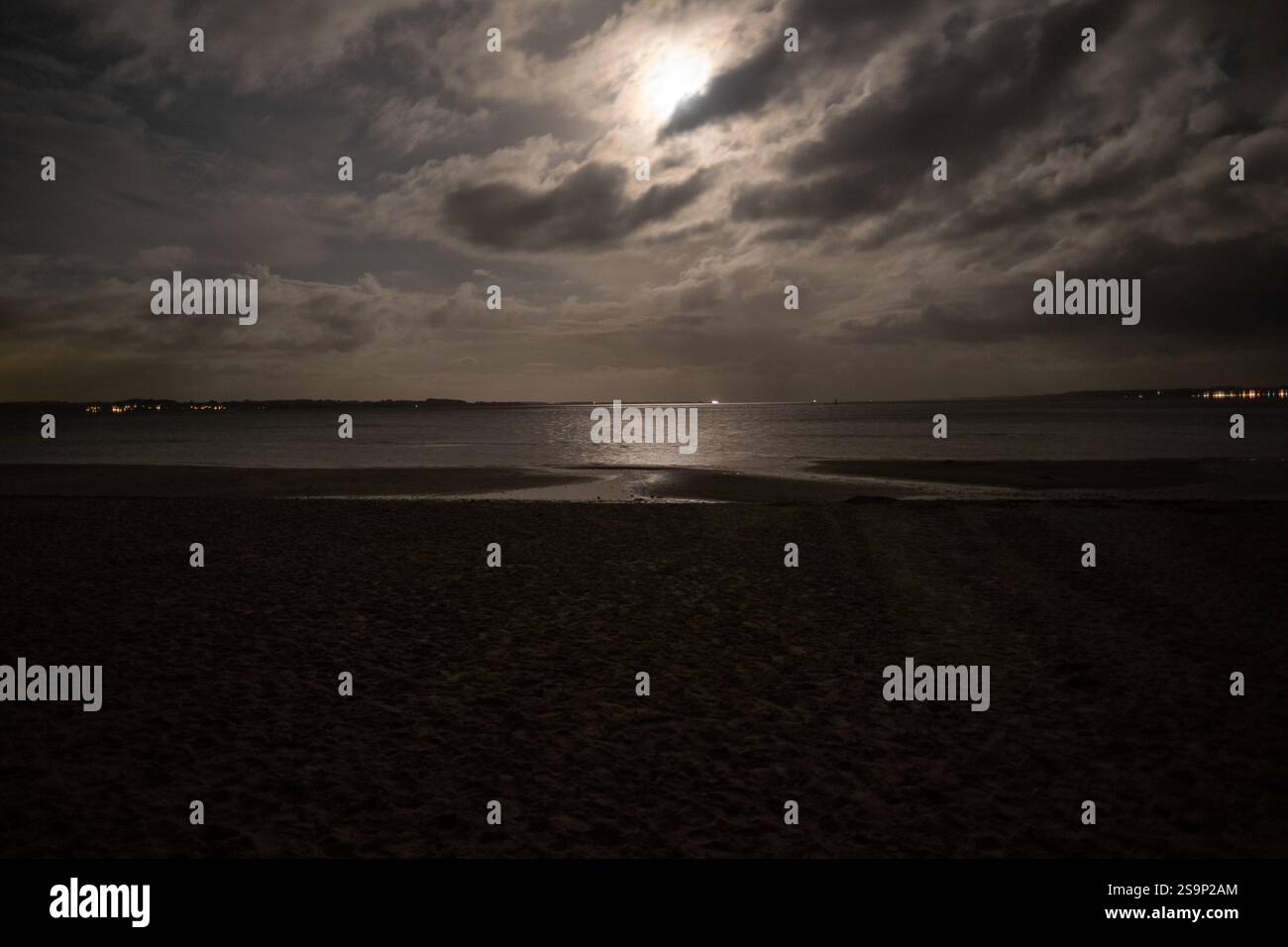 View of the full moon with clouds, the light is reflected in the Baltic ...