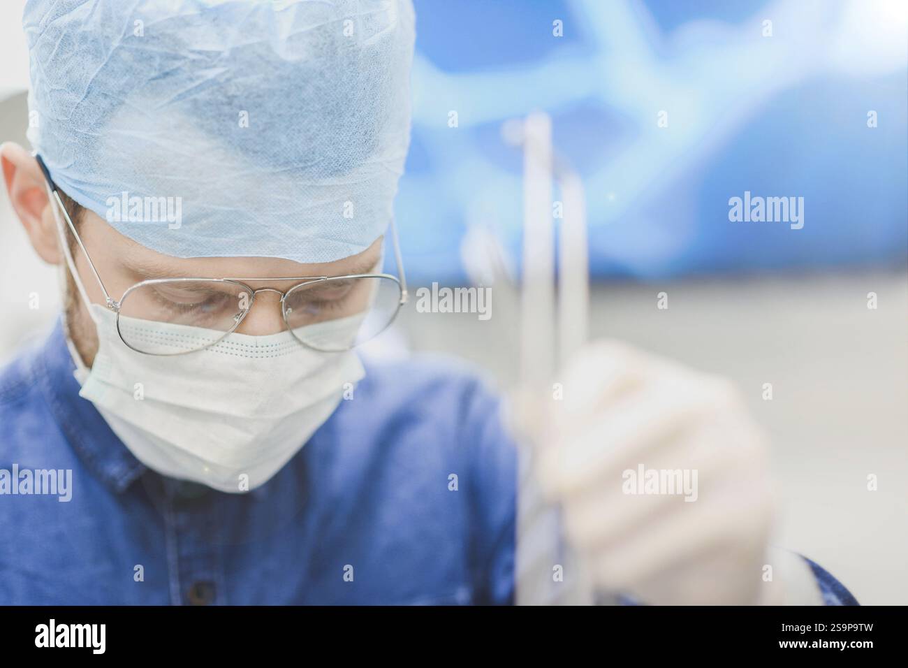 Doctor focused on surgical tools, blue-lit medical environment Stock ...