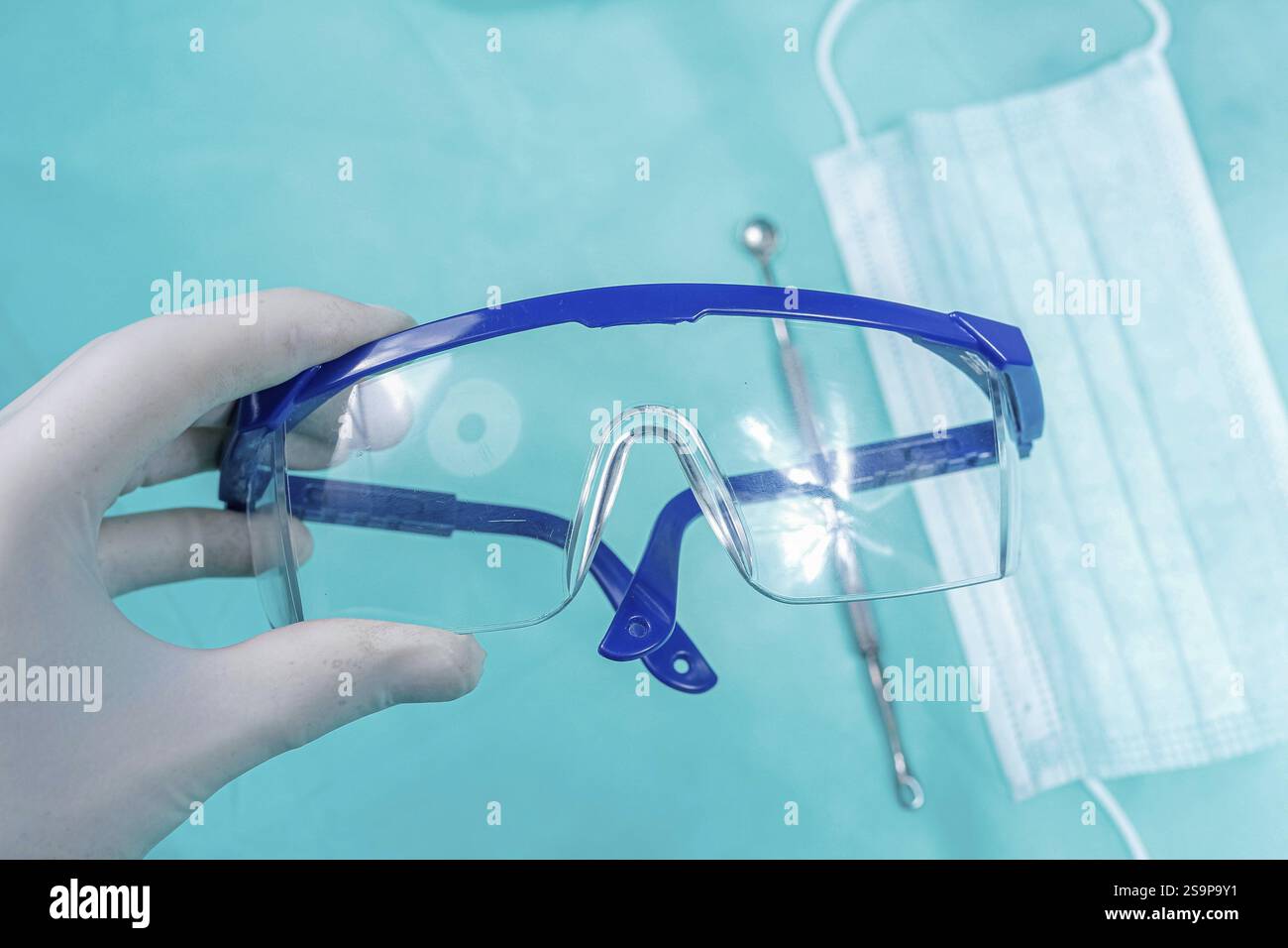 Hand holding eyewear above a blue background with medical accessories ...