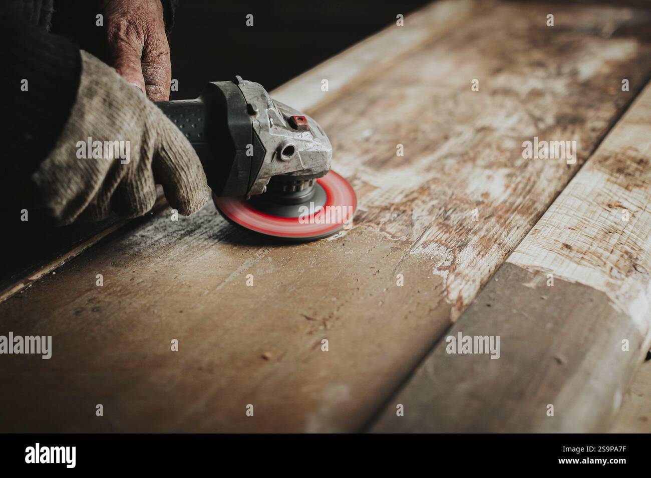 Gloved hands using a sanding tool on wood, focusing on surface texture ...
