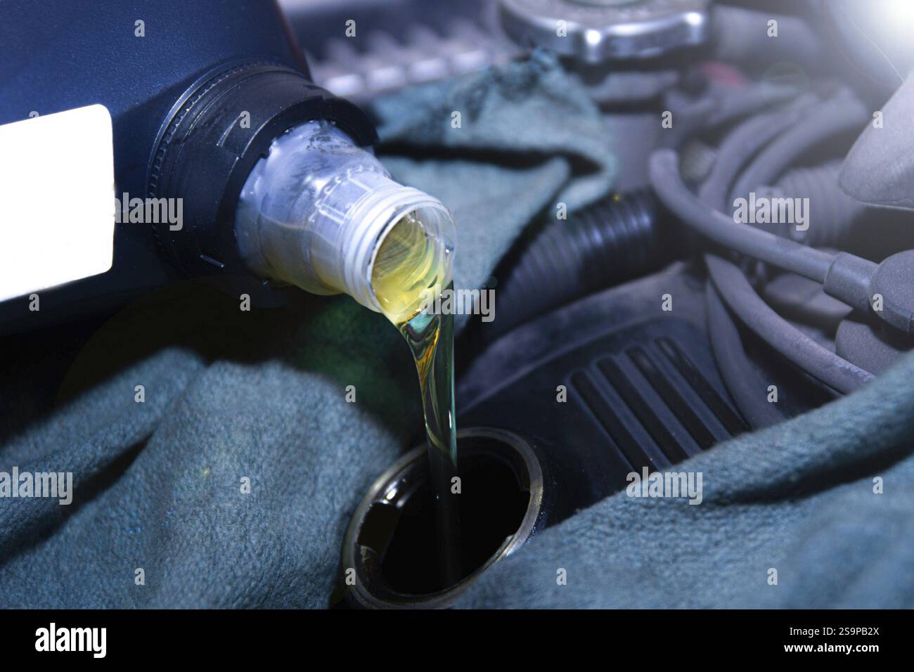 Motor oil being poured from a container into a car engine during ...
