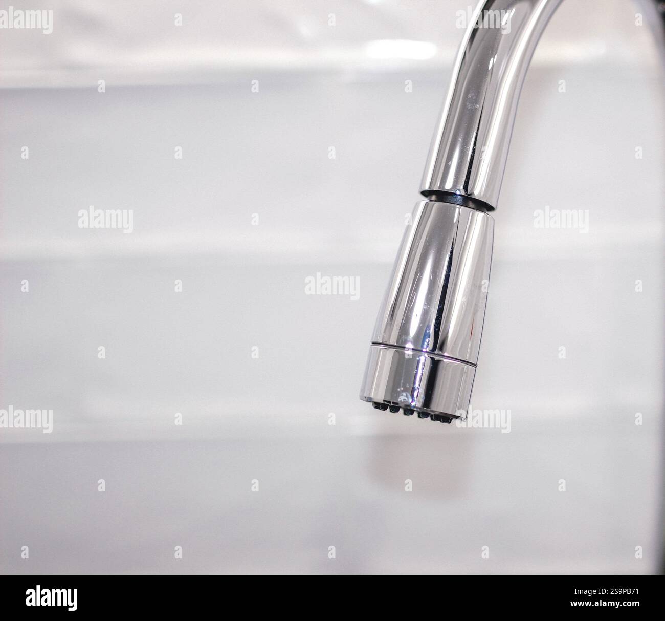 Chrome faucet extending from a tiled wall, showcasing its shiny design ...