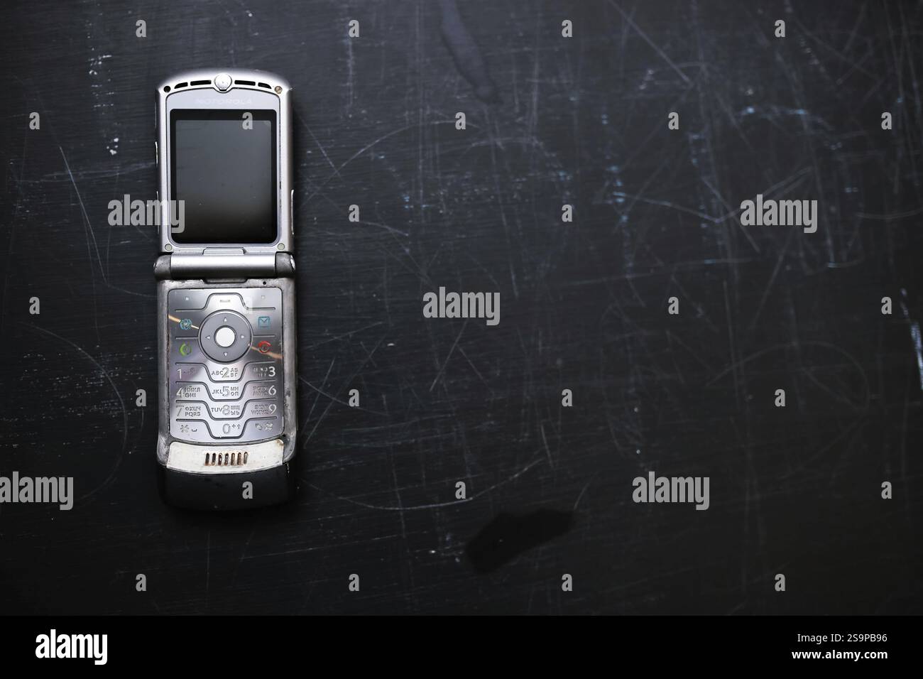 A silver Motorola RAZR flip phone on a scratched black surface Stock ...