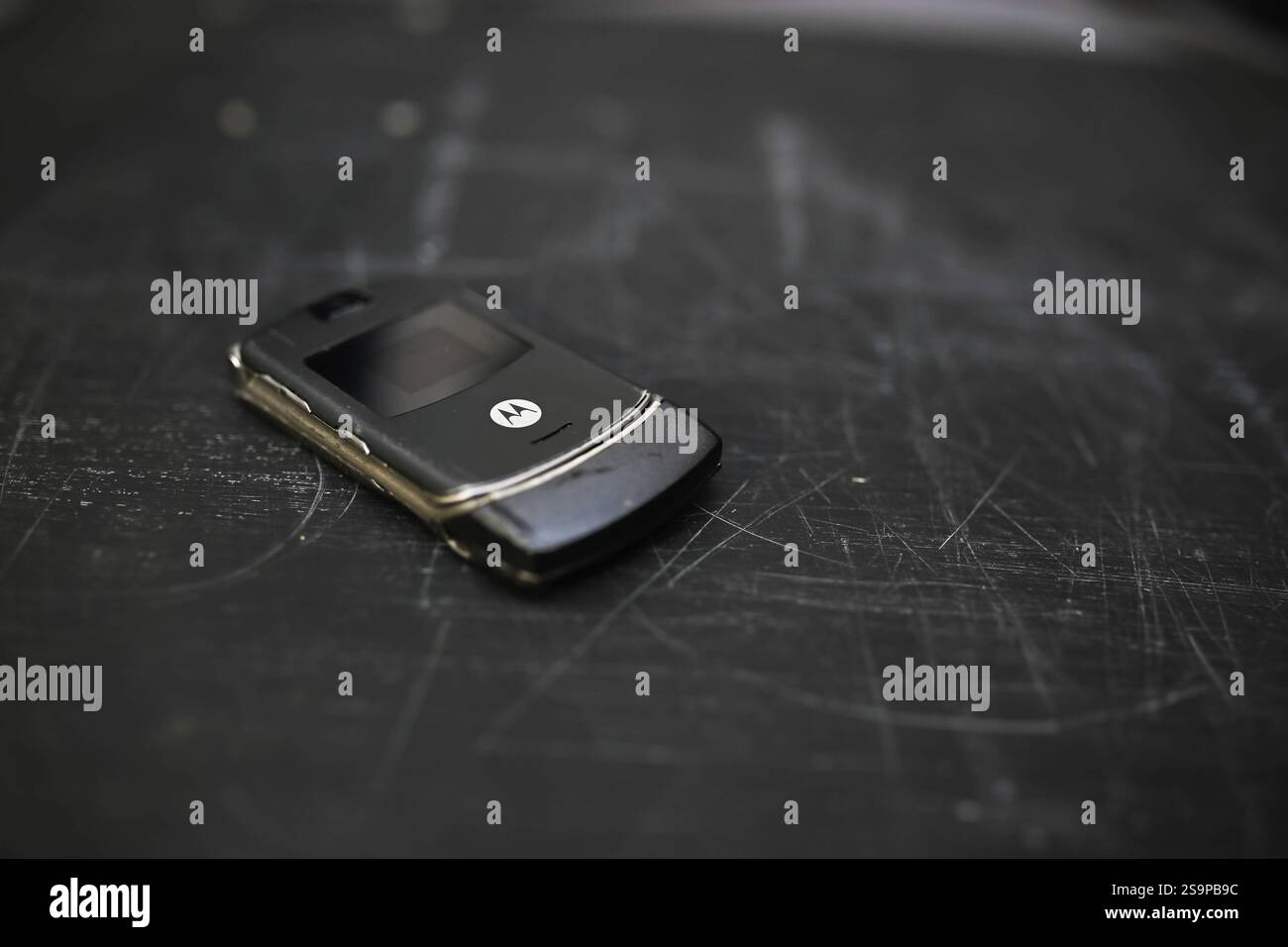 A closed Motorola flip phone resting horizontally on a dark surface ...