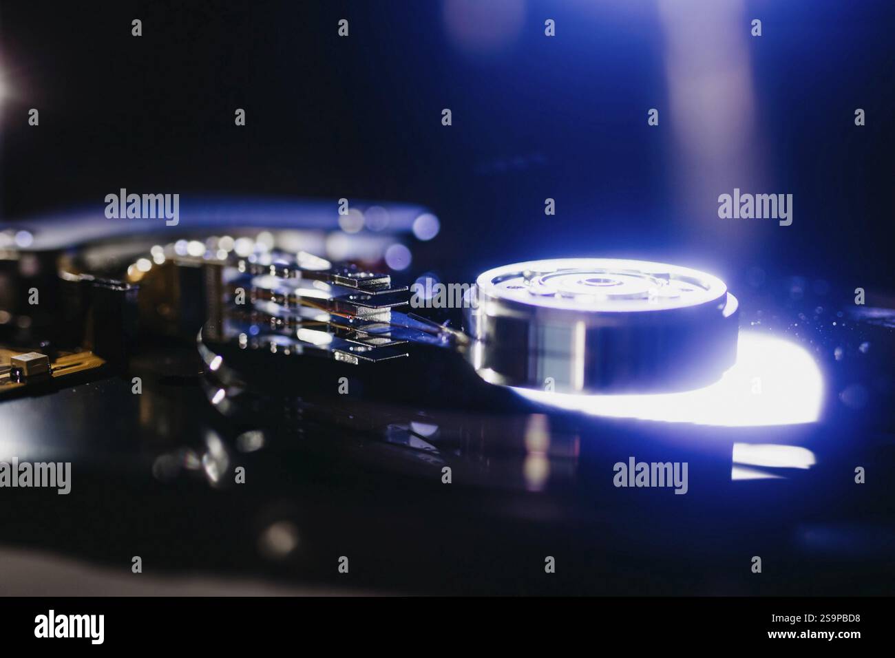 Hard drive platter illuminated by blue light, showcasing metal ...