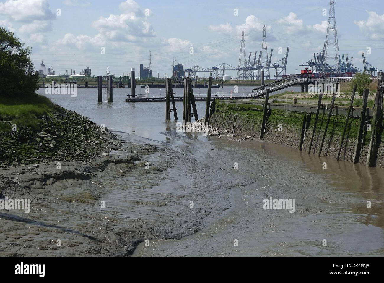 Muddy waterfront with a view of a harbour and industry, lillo, antwerp ...